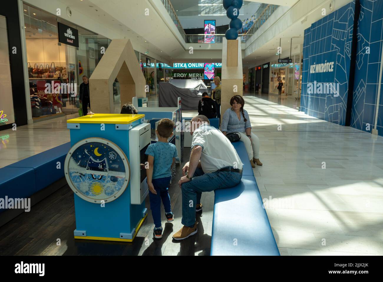 Two adults watching children playing at an indoor playground in the ...