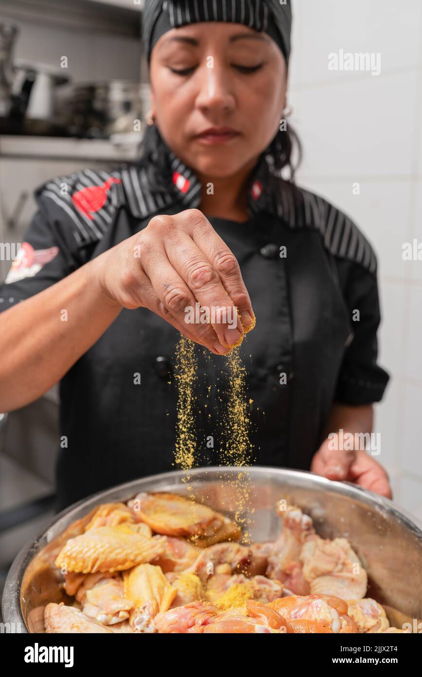Crop concentrated female chef in uniform pouring flavoring into bowl ...