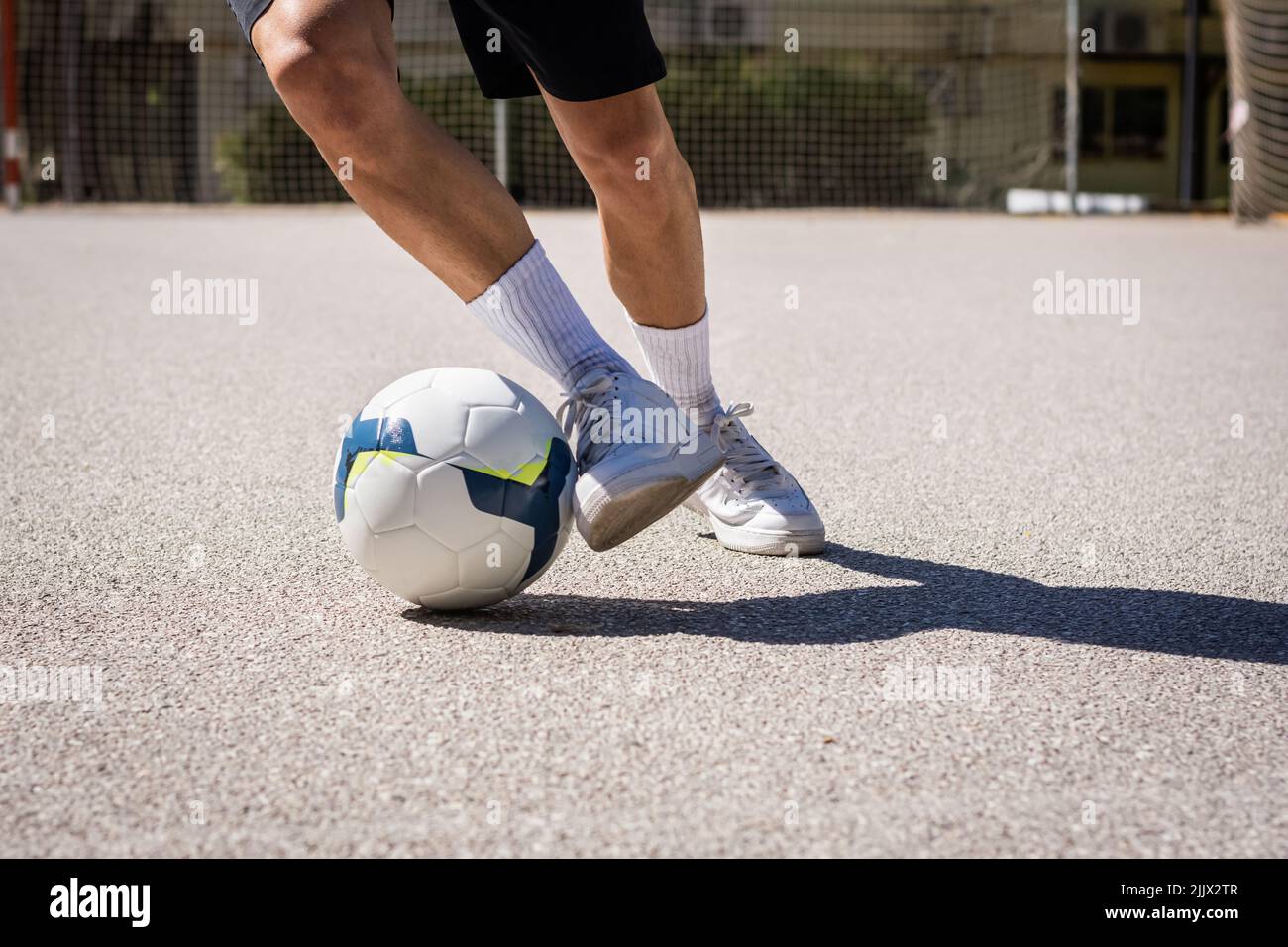 Cropped unrecognizable of male athlete with leg on soccer ball while ...