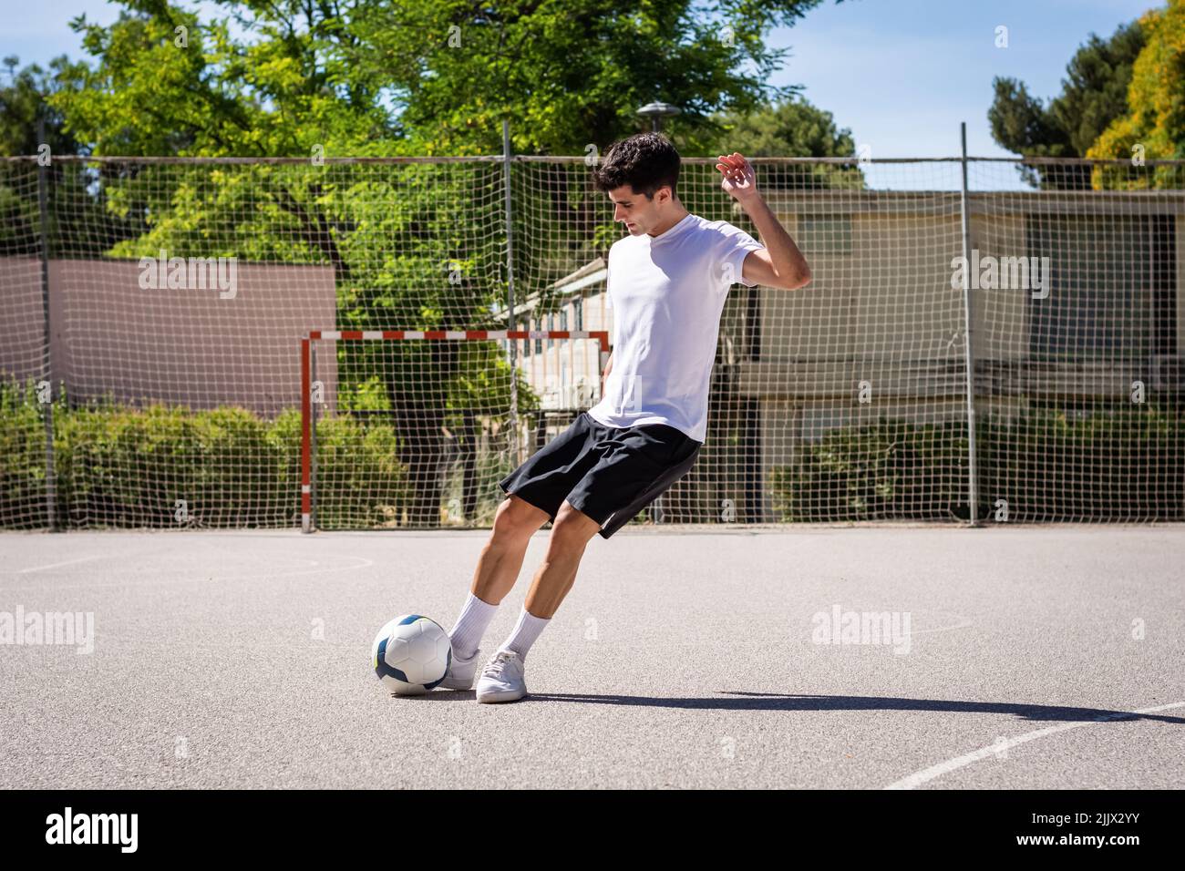 Full body of young male athlete kicking ball while playing soccer Stock ...