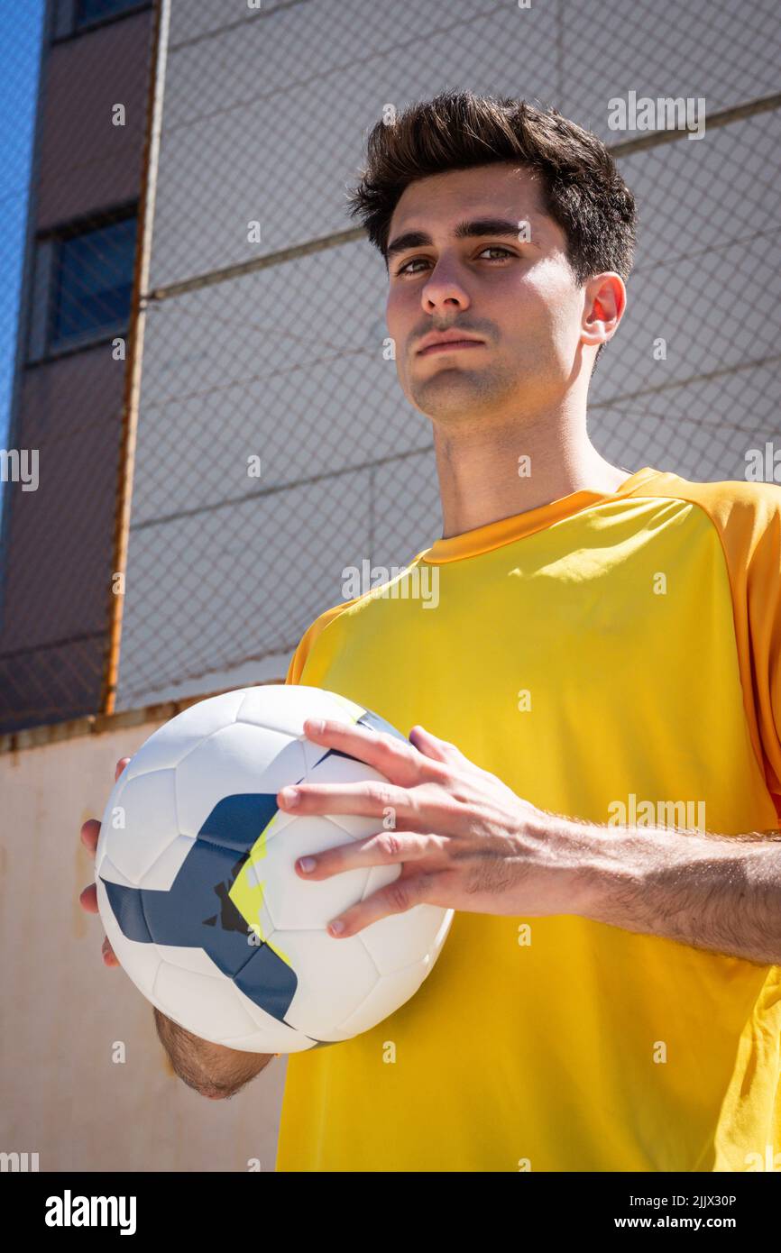 Portrait of handsome young male soccer player holding football while ...