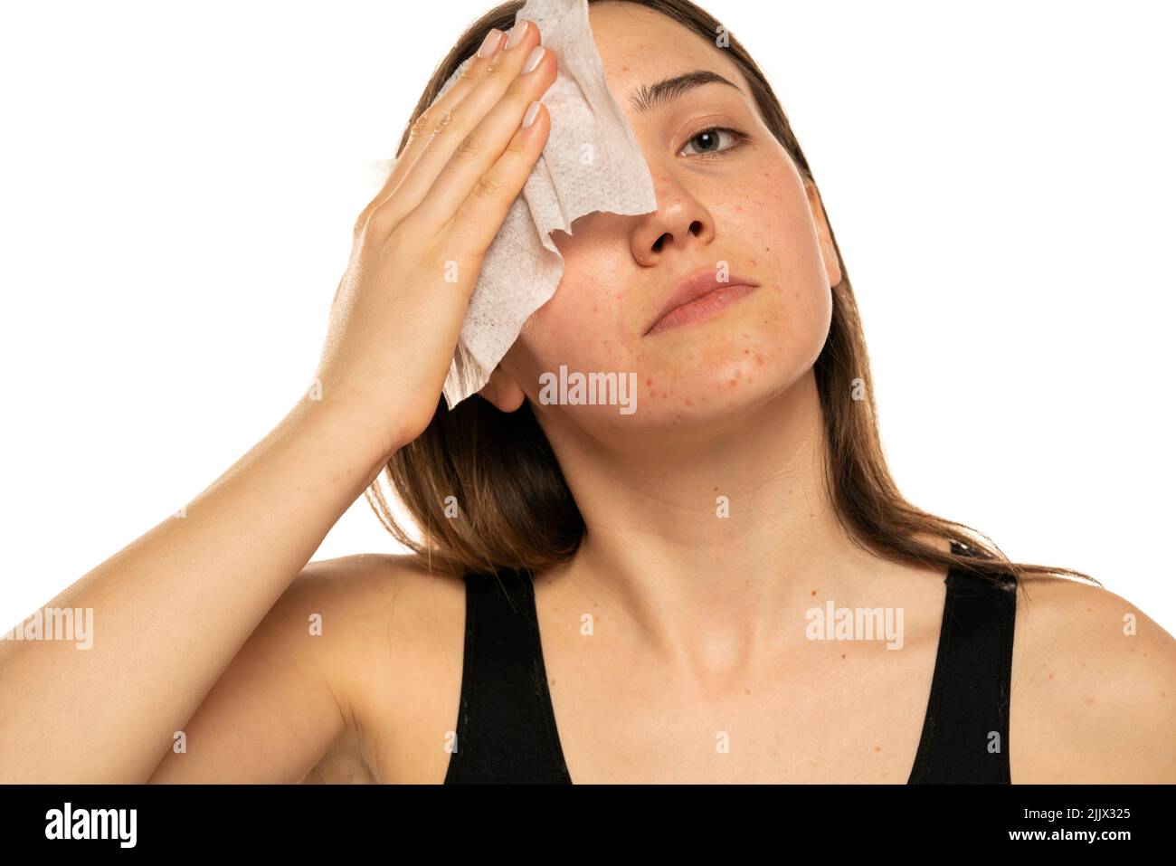 Young woman cleaning her face with wet wipe on white background Stock ...