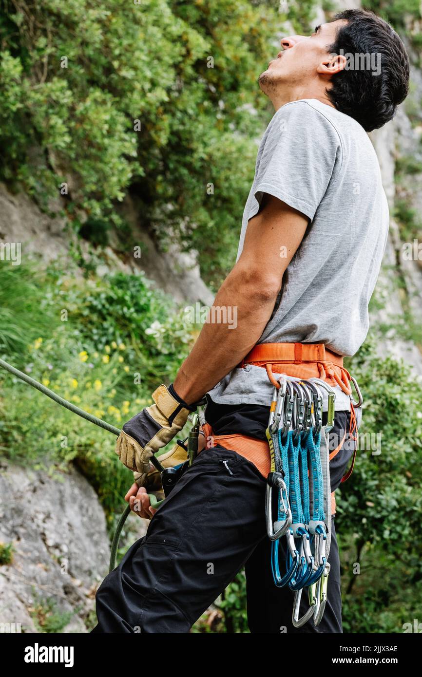 Side view of man holding safety cable looking above while belaying highlander Stock Photo - Alamy