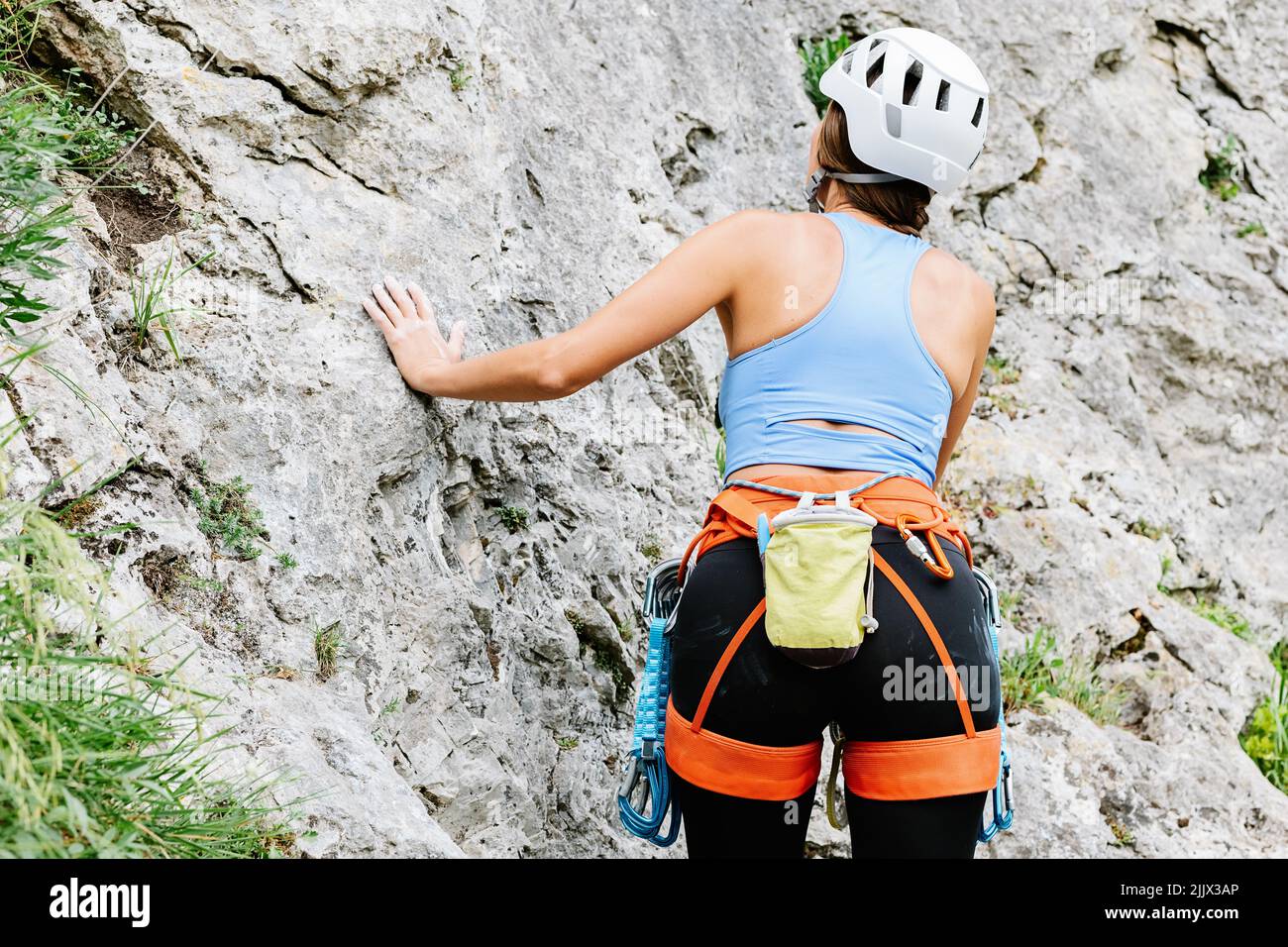 Back view female hiker wearing harness and helmet while climbing on ...