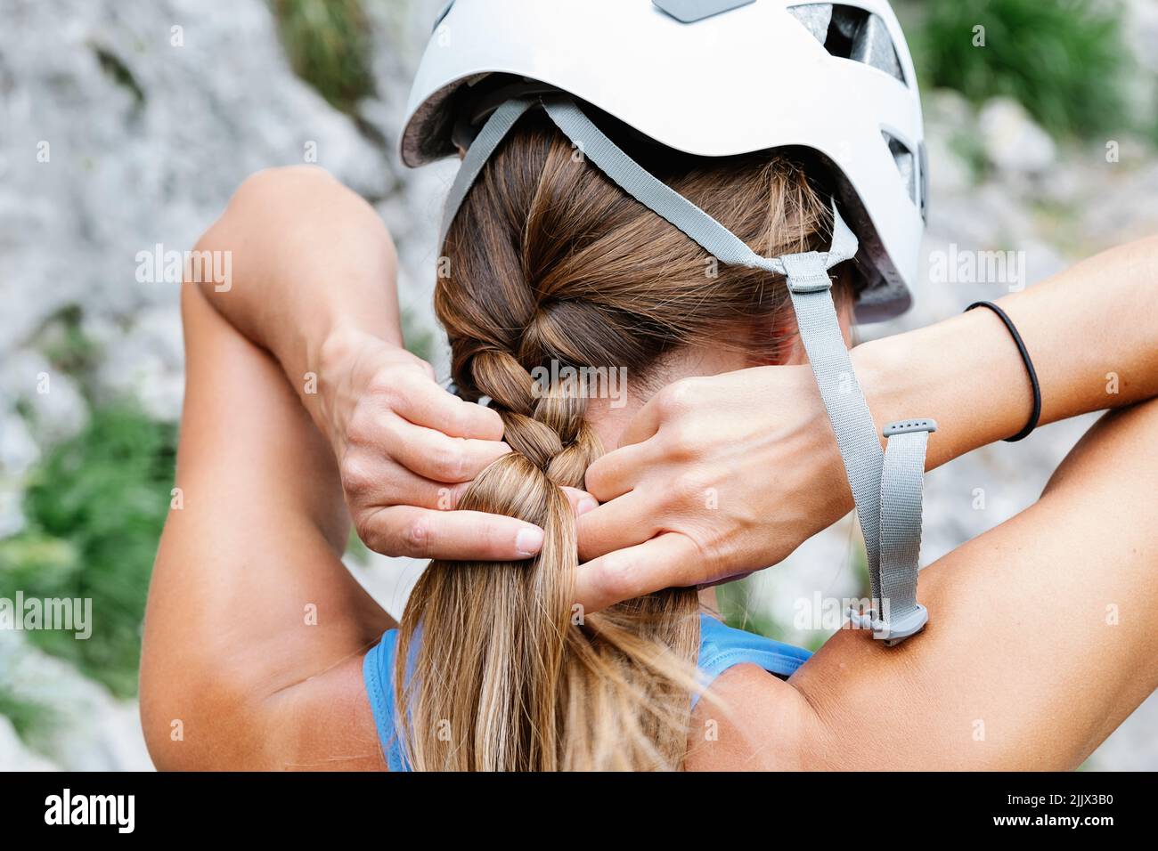 Rear view of Woman with safety helmet tying braid while preparing for ...
