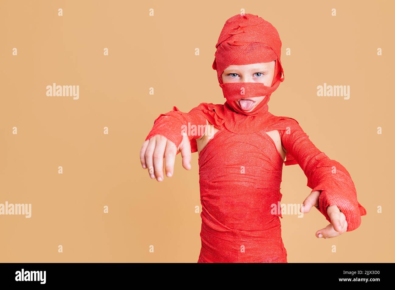 Little boy in red mummy costume making face and raising arms while ...