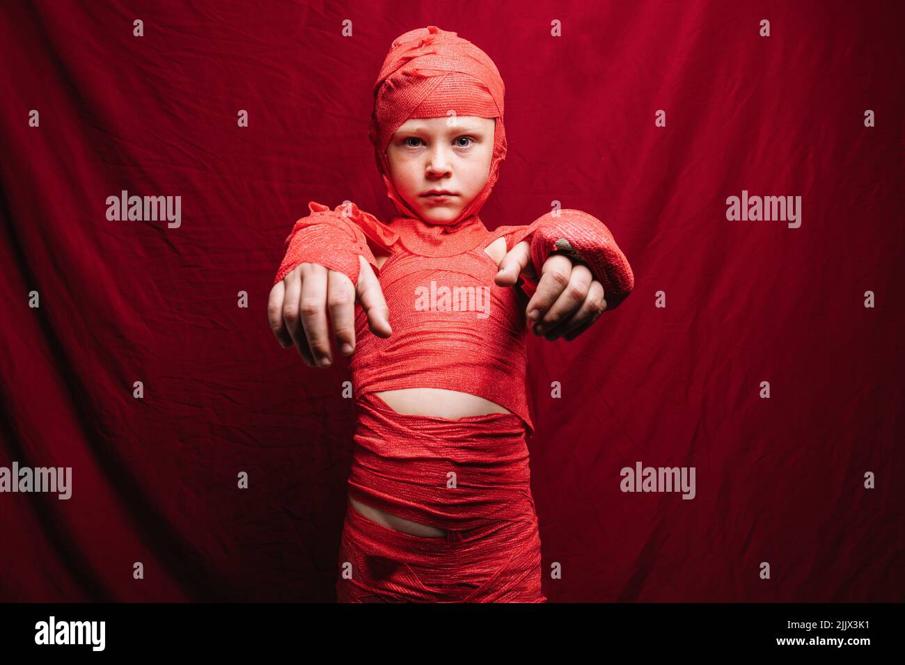 Adorable little boy in red mummy costume making scary face and reaching ...