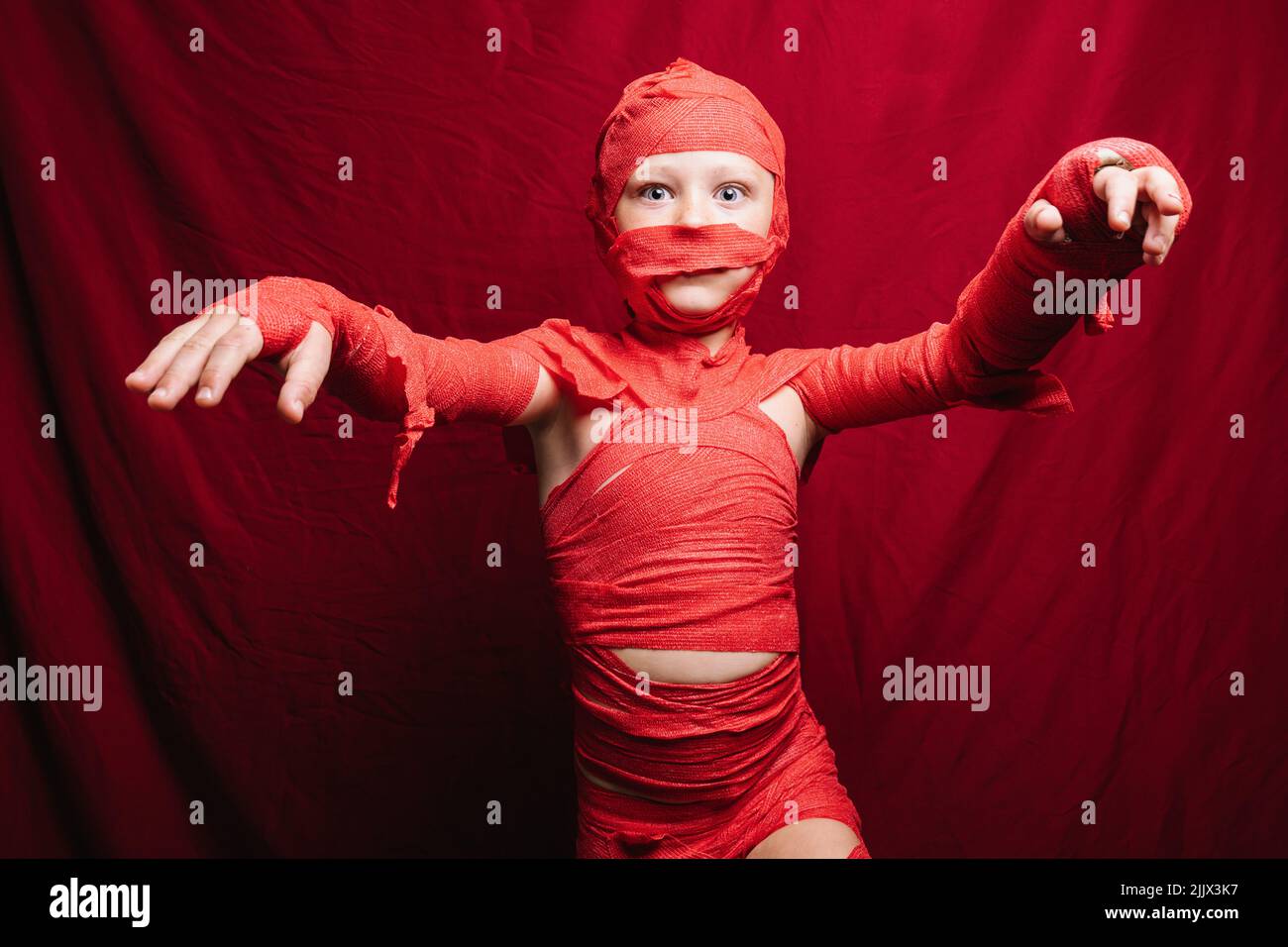 Adorable little boy in red mummy costume making scary face and reaching ...