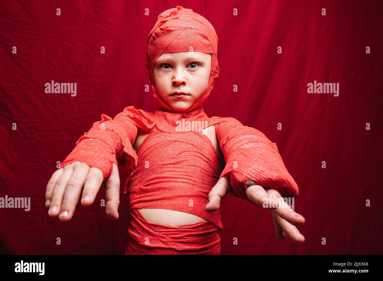Adorable little boy in red mummy costume making scary face and reaching ...