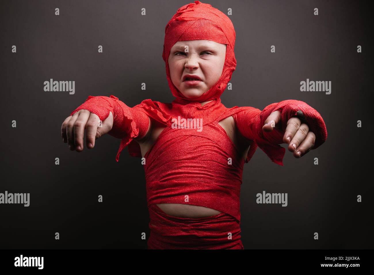 Adorable little boy in red mummy costume making scary face and reaching ...