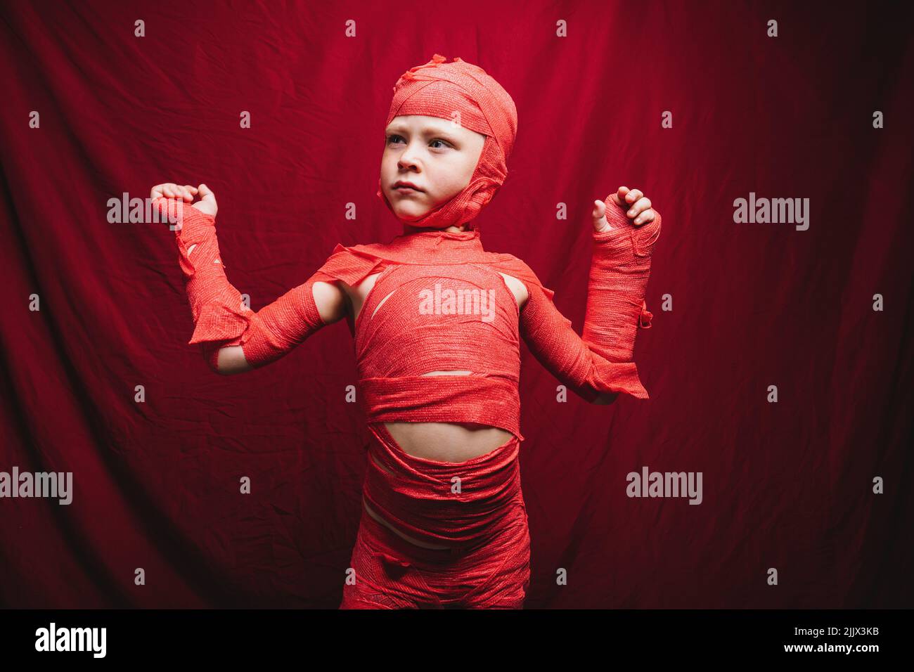 Adorable little boy in red mummy costume making scary face with arms ...