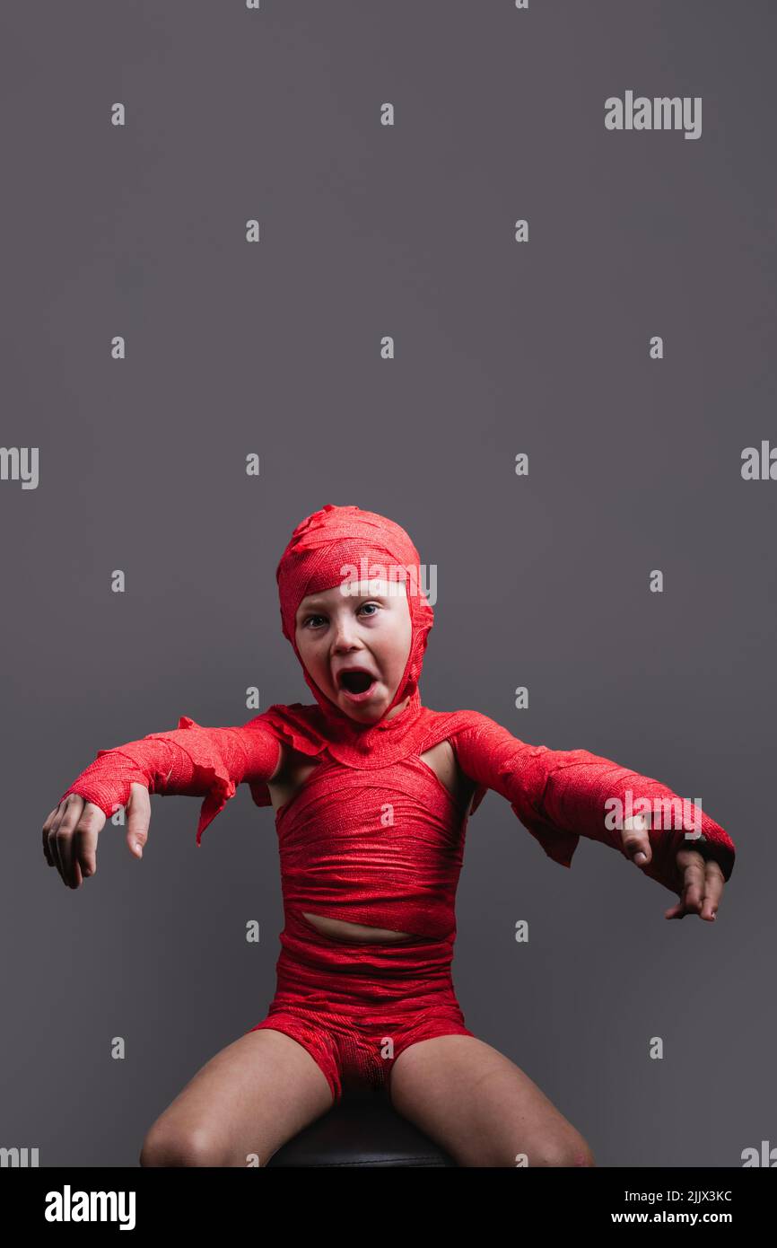 Adorable little boy in red mummy costume making scary face and reaching ...