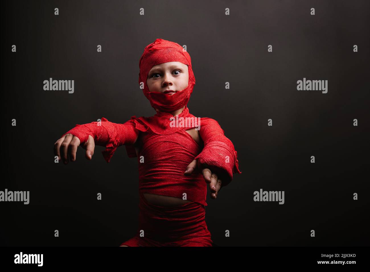Adorable little boy in red mummy costume making scary face and reaching ...