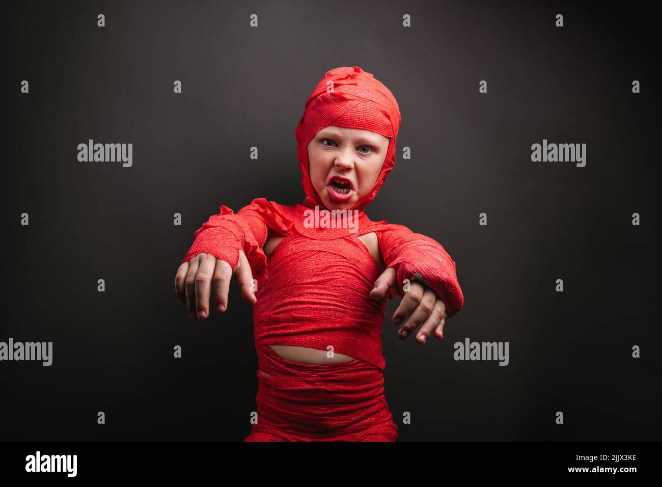 Adorable little boy in red mummy costume making scary face and reaching ...