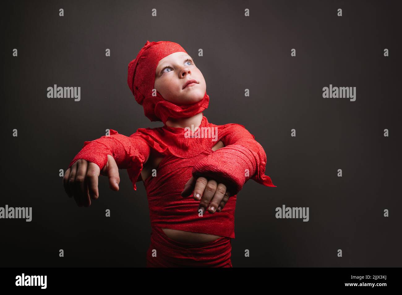 Adorable little boy in red mummy costume making scary face and reaching ...