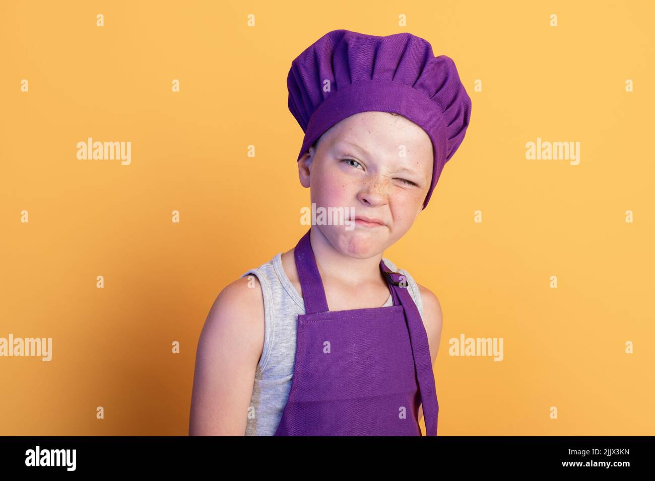Adorable positive little boy with funny face in purple chef apron and ...