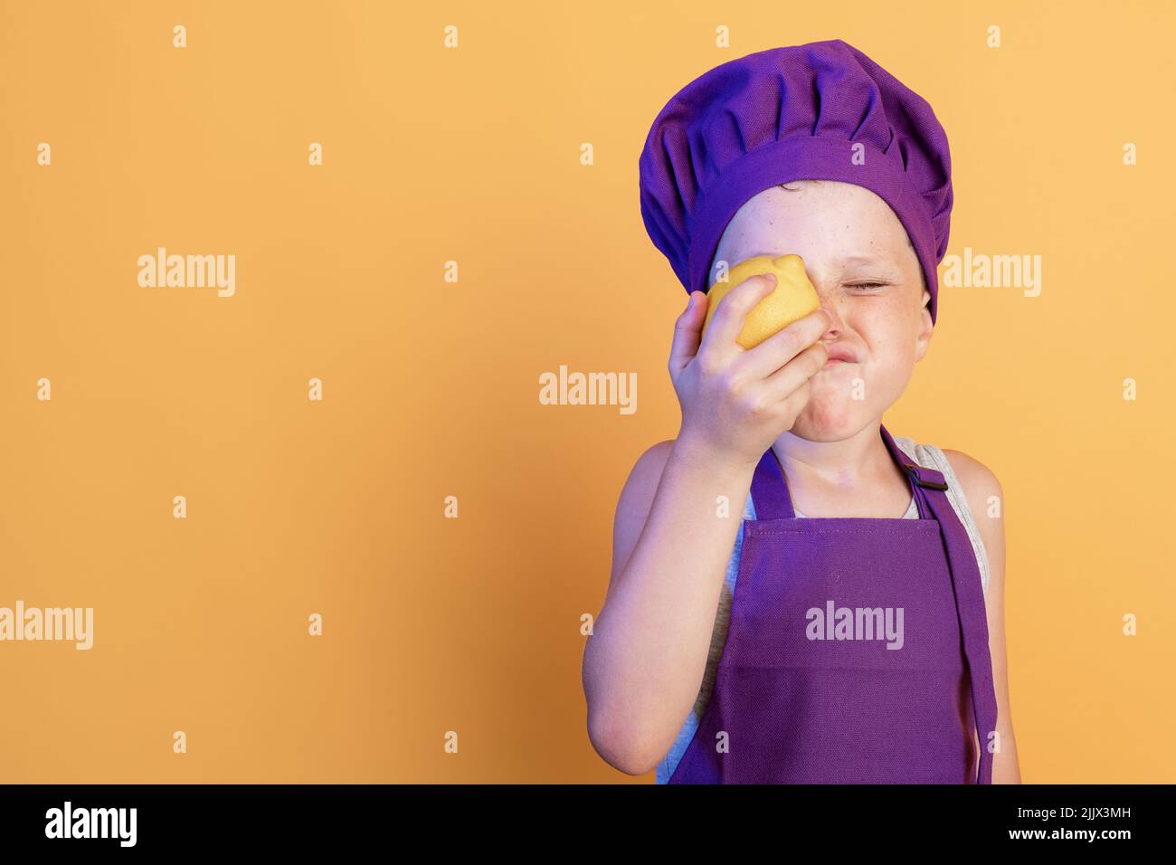 Adorable little boy in purple chef apron and hat making funny face ...