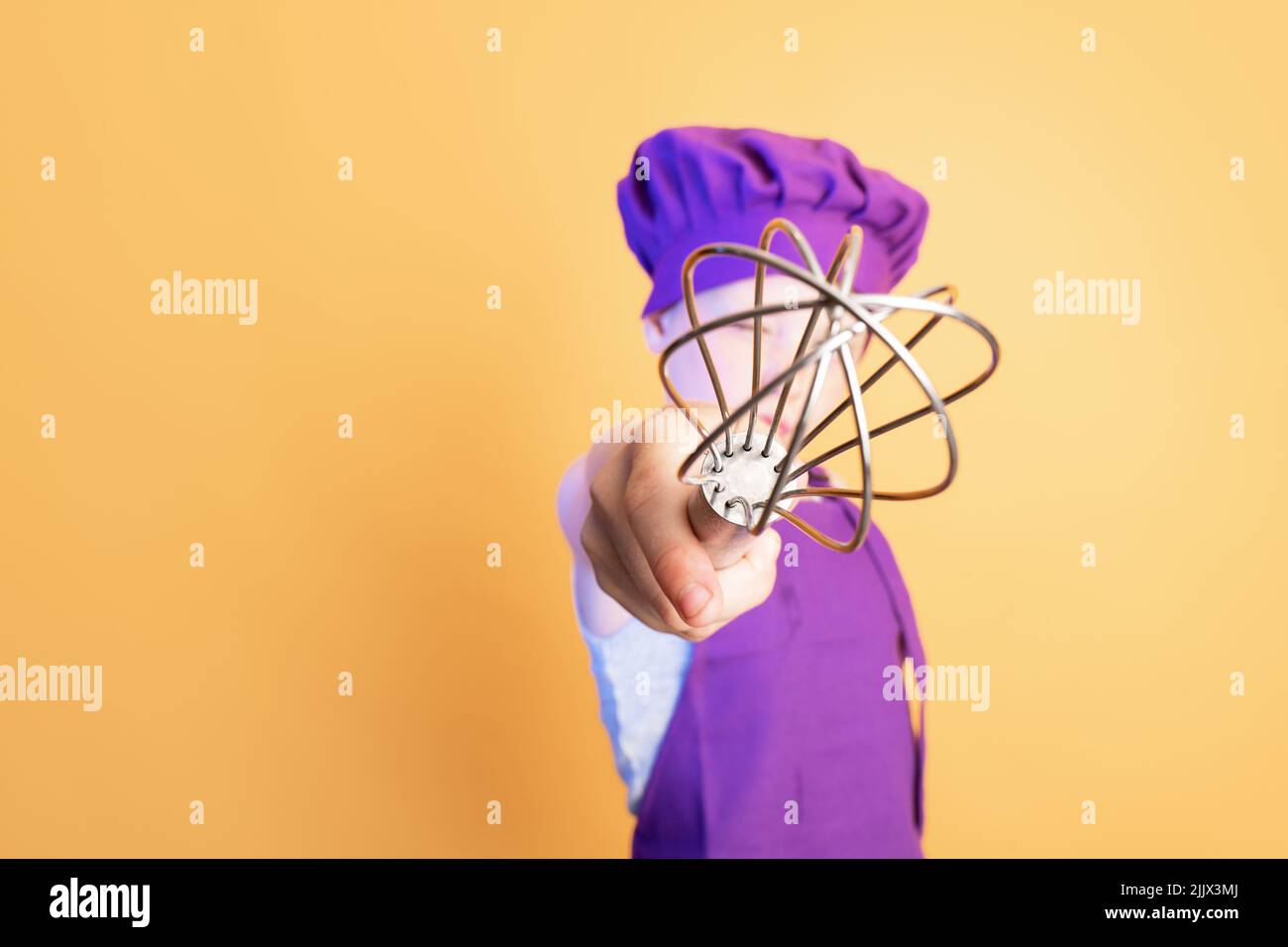 Unrecognizable little child in bright purple chef apron and hat ...