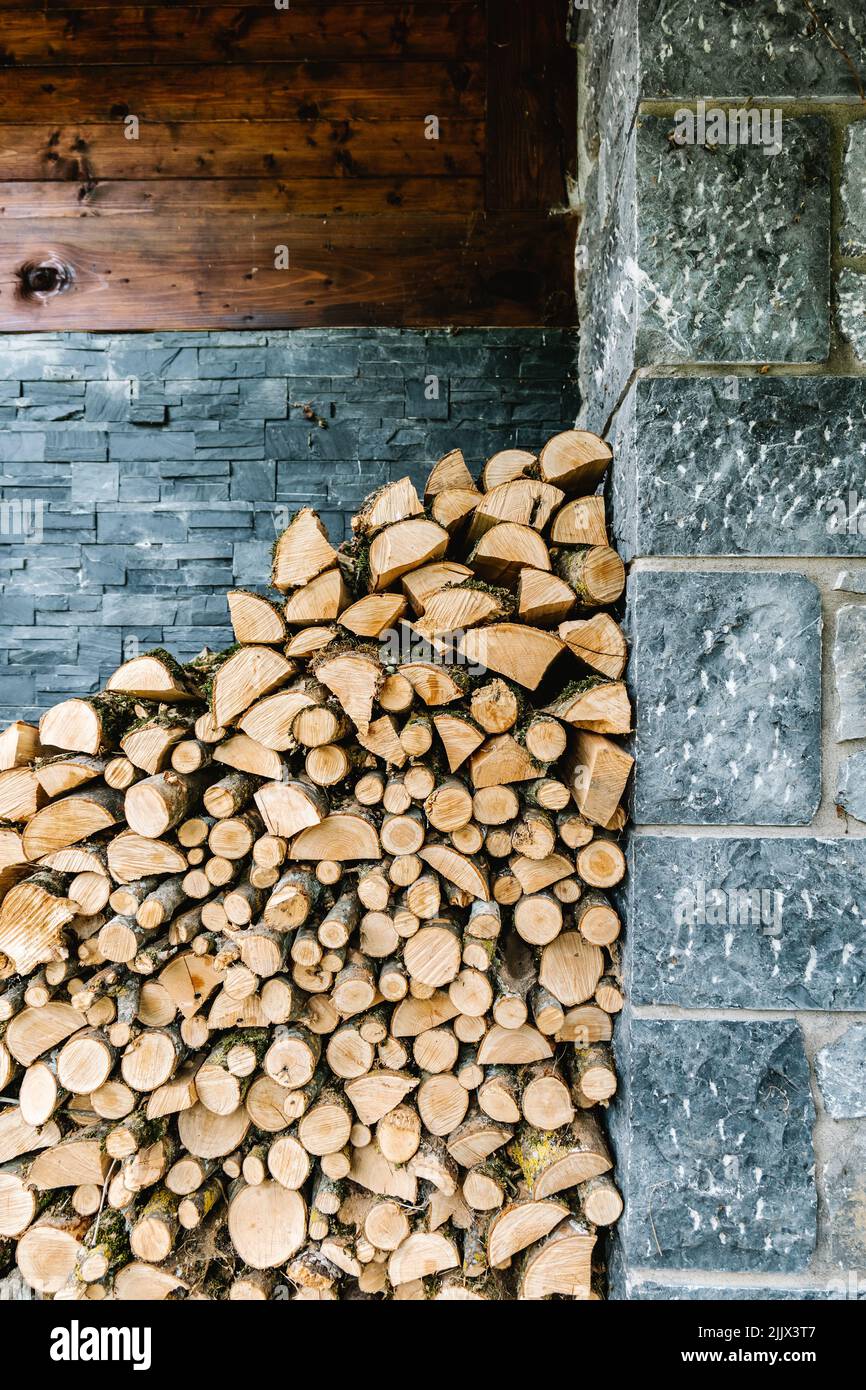 Pile of chopped firewood stacked near stone wall in house in daytime in ...