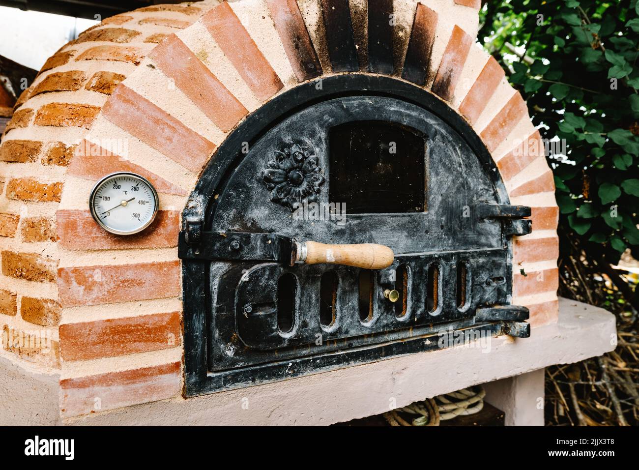Traditional aged brick furnace with iron door located in wooden gazebo ...