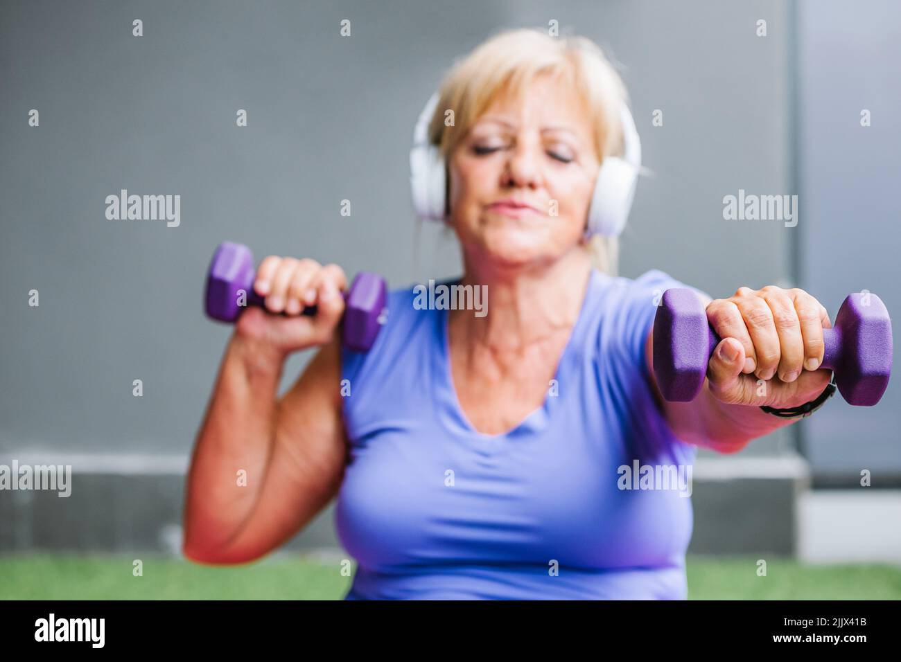 Fit senior Woman exercising with purple dumbbells representing active ...
