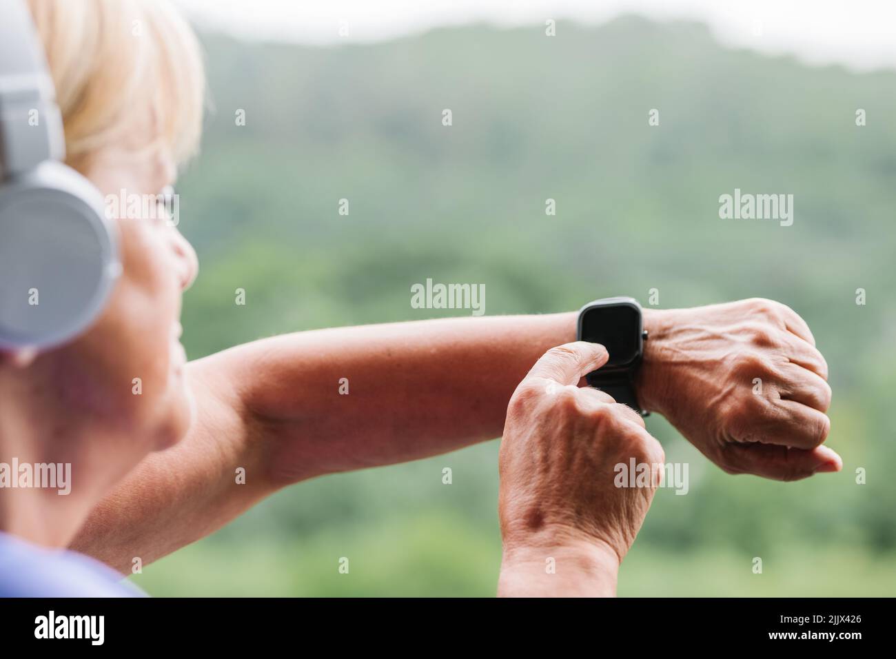 Hands of senior Woman setting up the fitness smart watch and headphones ...