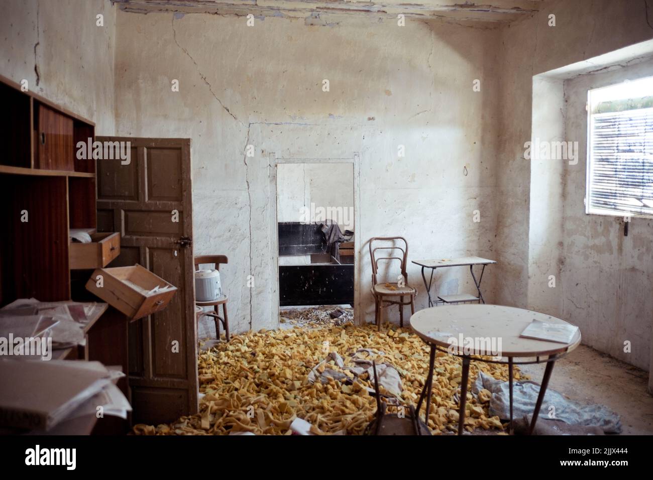 Dirty furniture surrounded with garbage inside sunlit abandoned ...