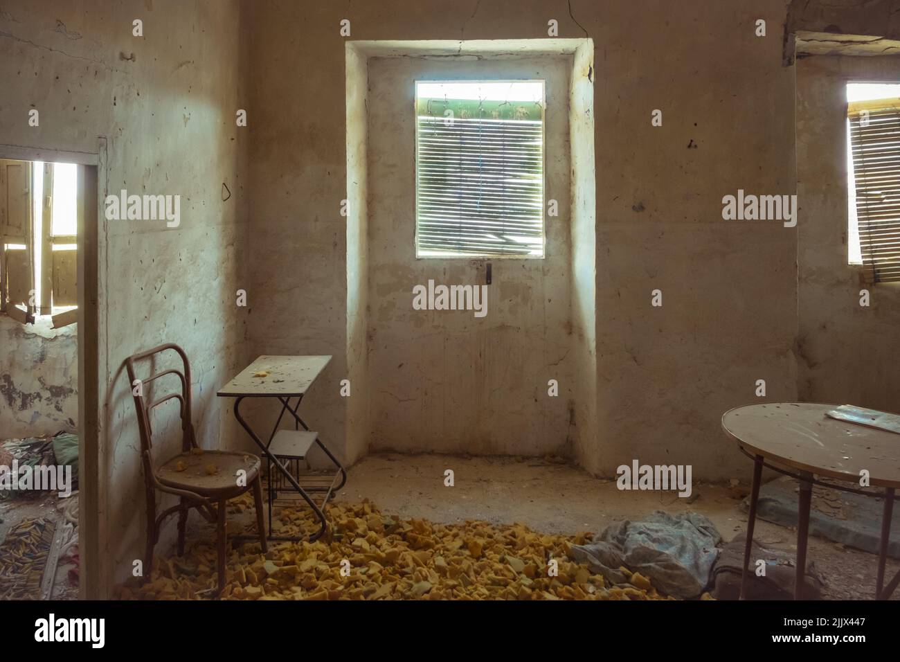 Dirty furniture surrounded with garbage inside sunlit abandoned ...