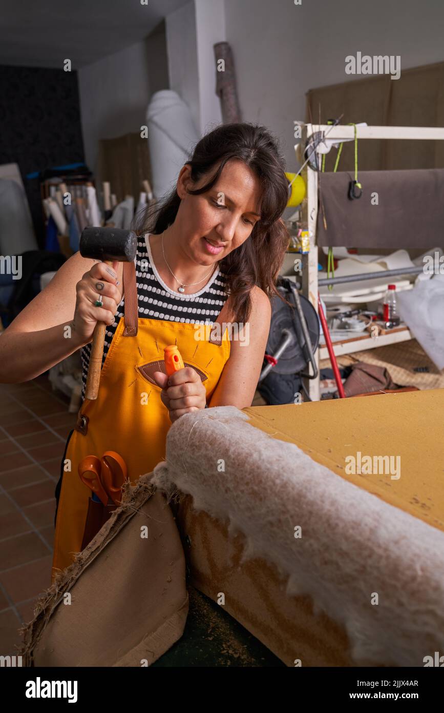 Concentrated adult female master with dark hair in apron hitting on ...