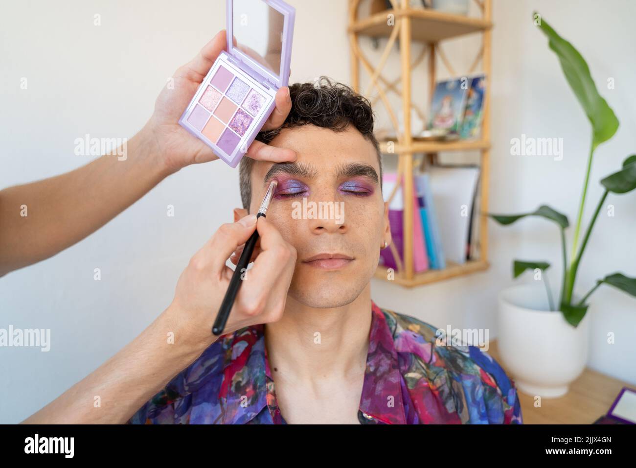 Caucasian transgender man getting makeup done by his boyfriend at home ...