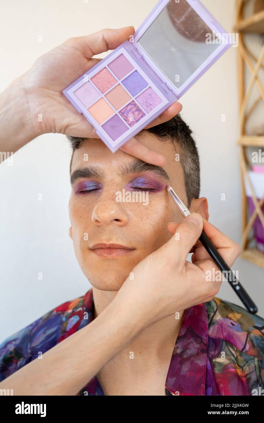 Caucasian transgender man getting makeup done by his boyfriend at home ...