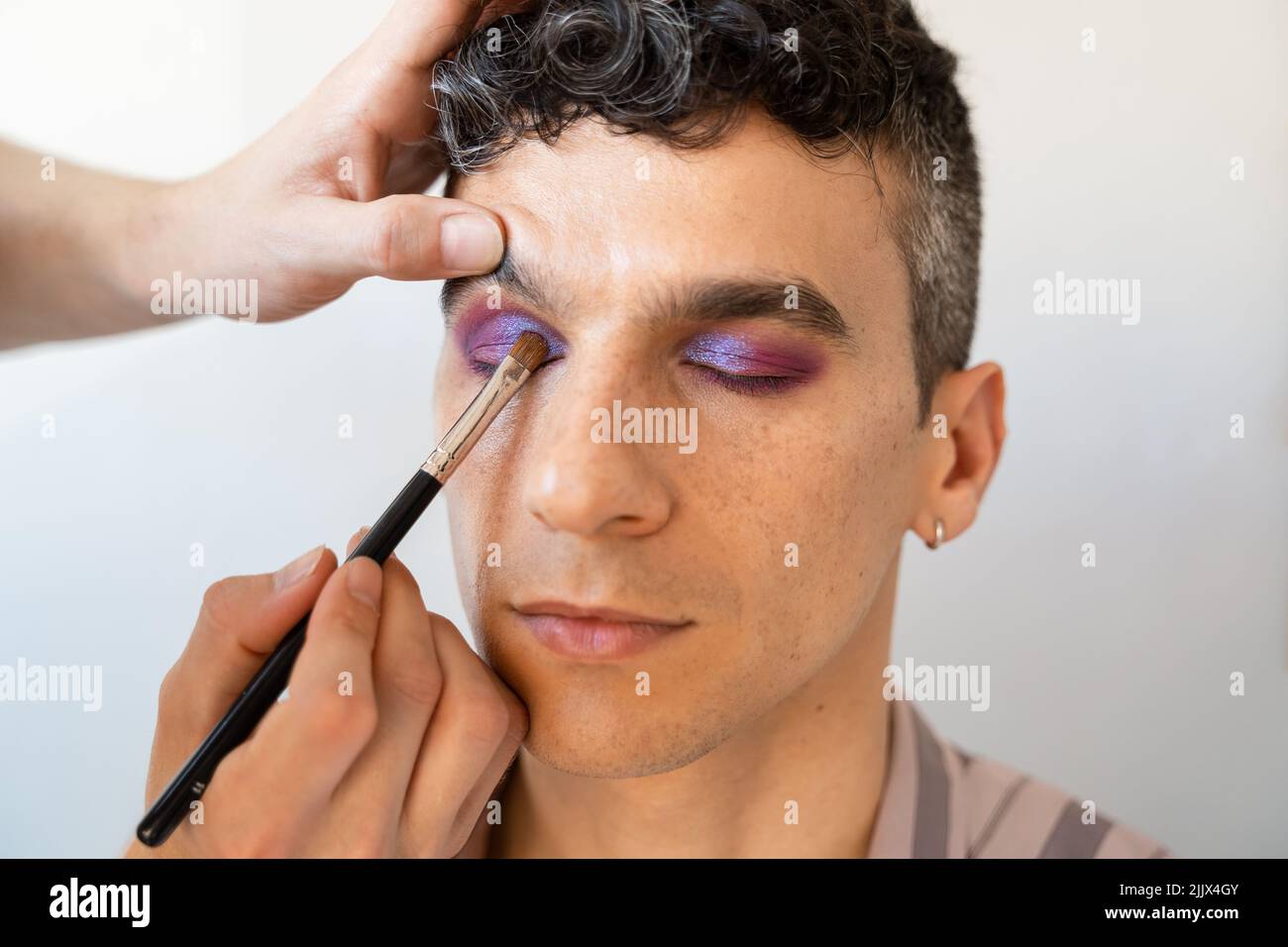 Caucasian transgender man getting makeup done by his boyfriend at home ...