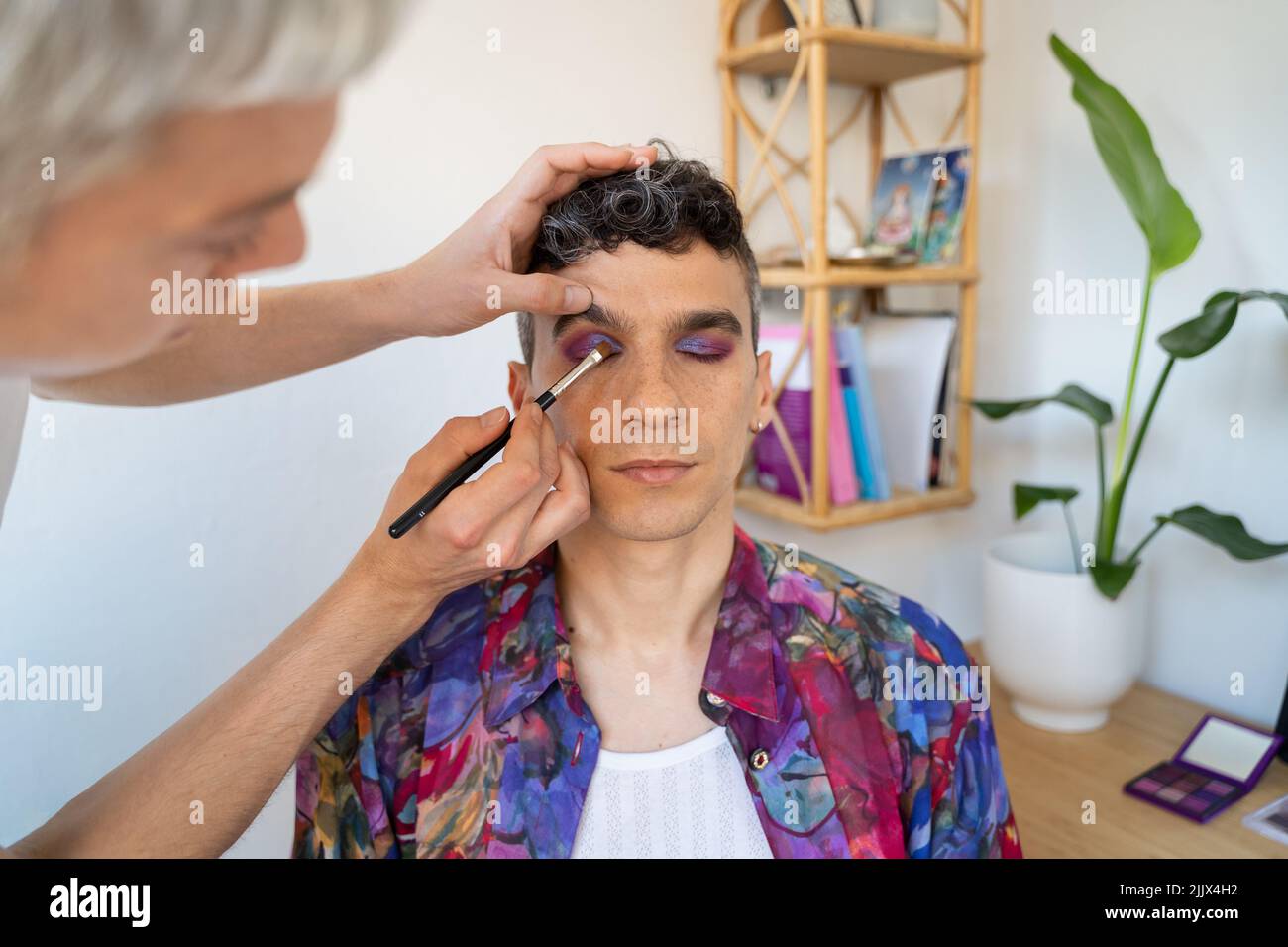 Caucasian transgender man getting makeup done by his boyfriend at home ...