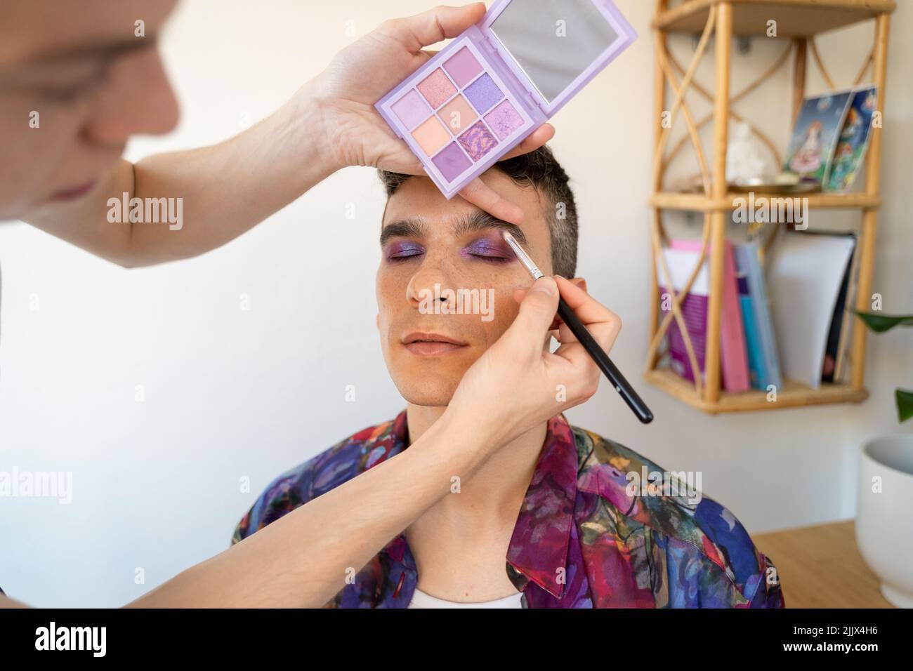 Caucasian transgender man getting makeup done by his boyfriend at home ...