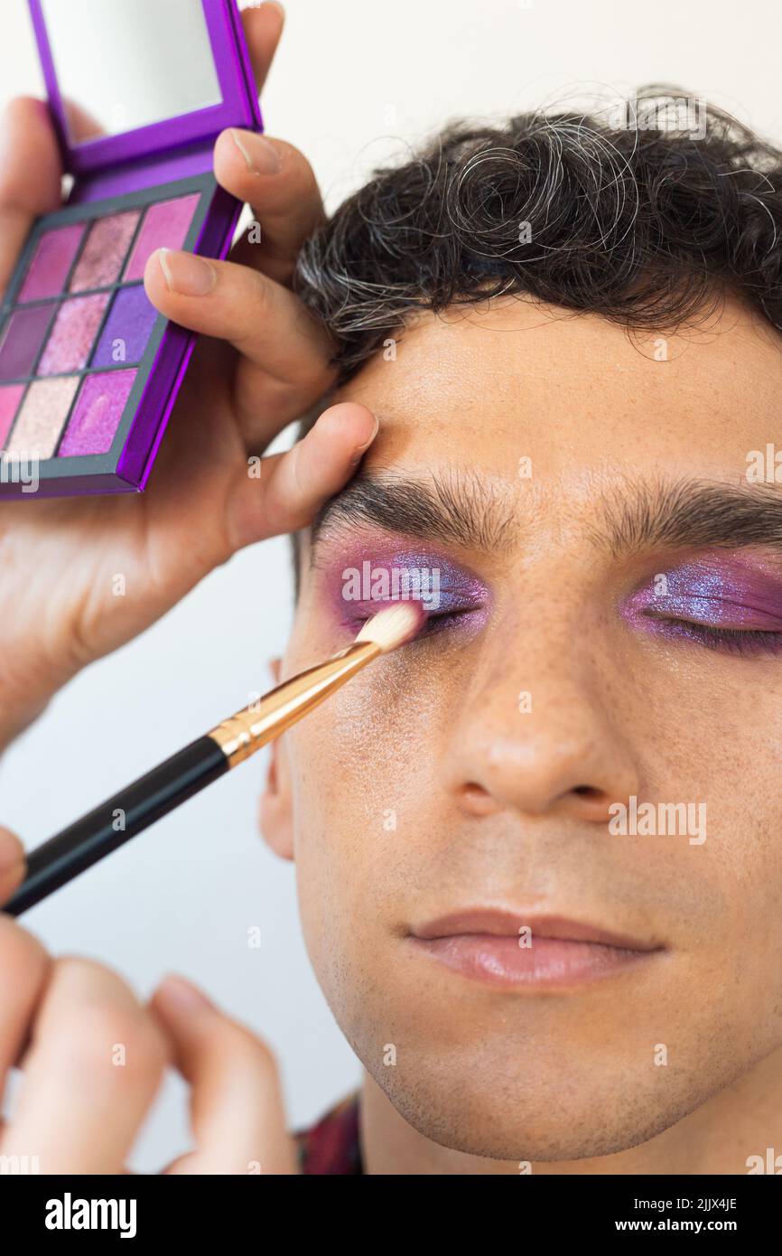 Caucasian transgender man getting makeup done by his boyfriend at home ...