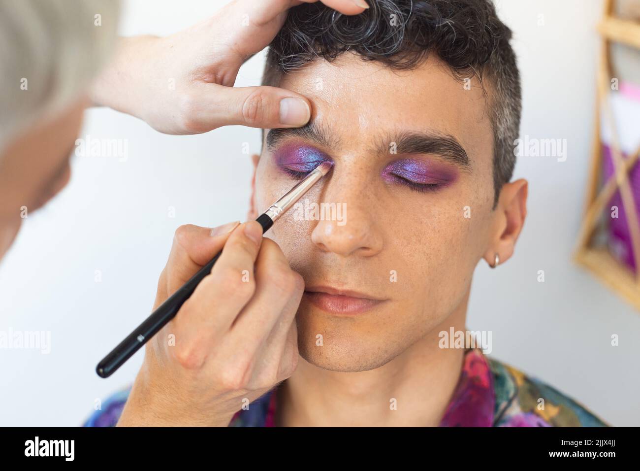 Caucasian transgender man getting makeup done by his boyfriend at home ...