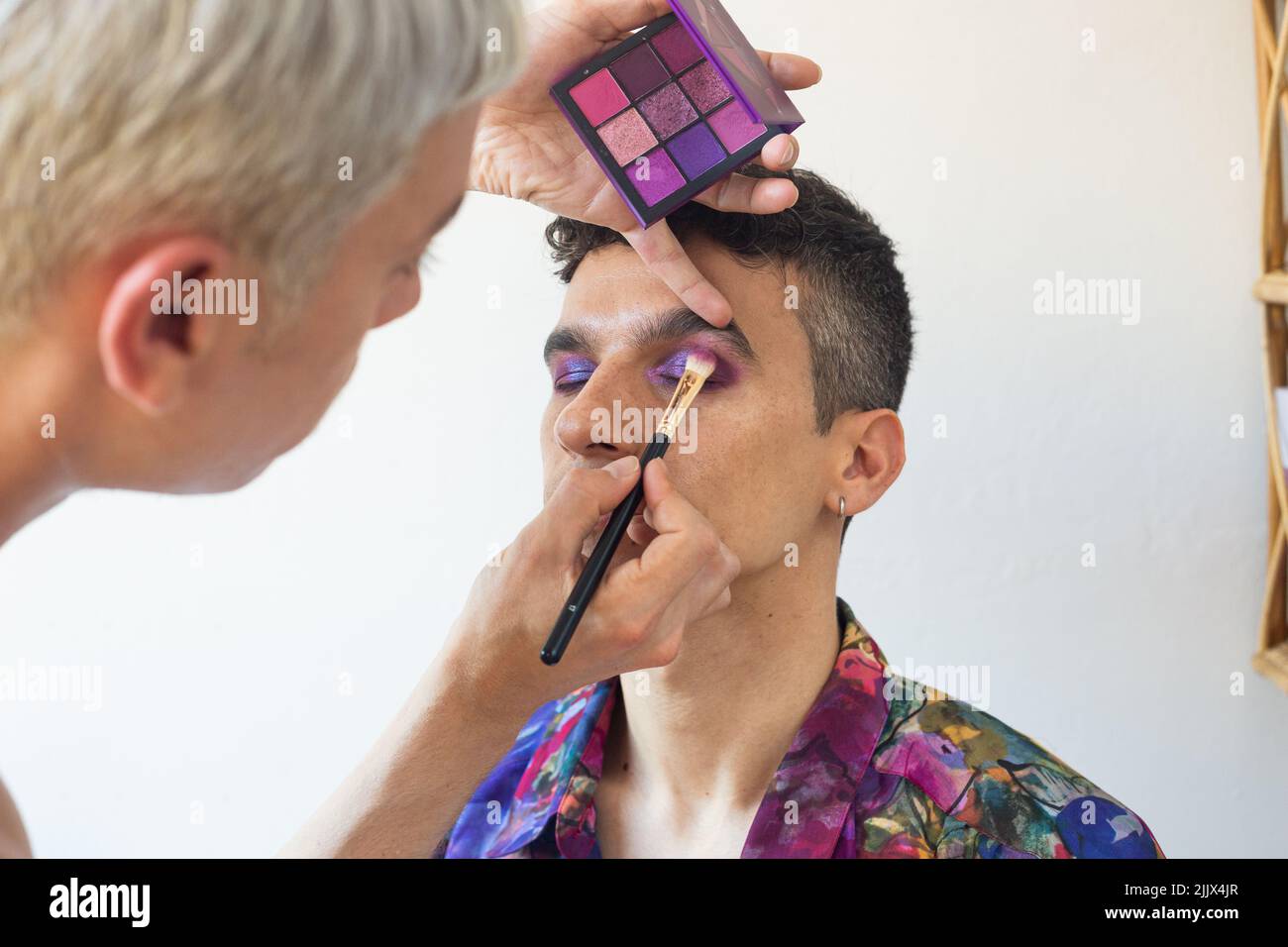 Caucasian transgender man getting makeup done by his boyfriend at home ...