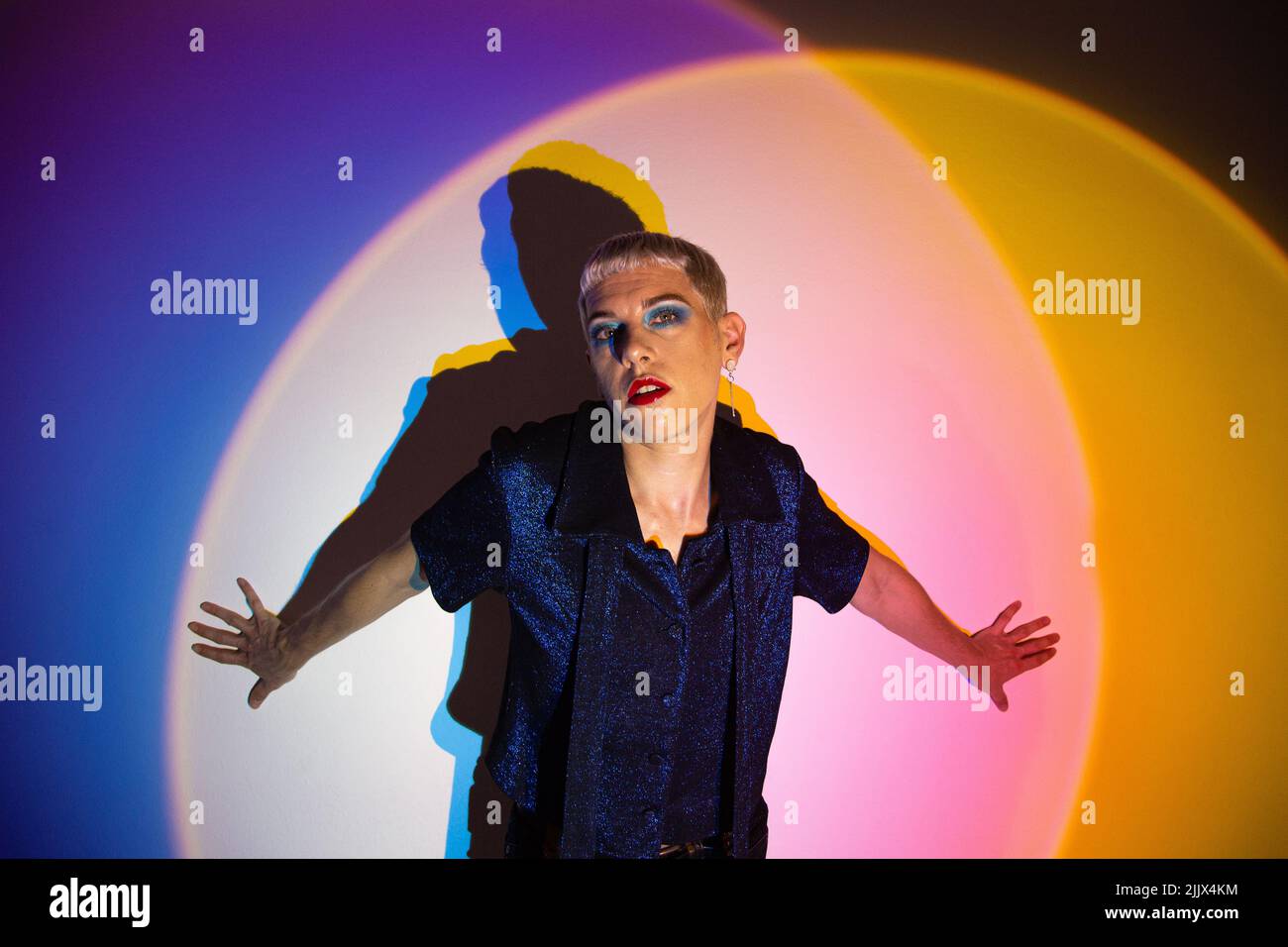 Transgender male standing arms outstretched performing in illuminated ...