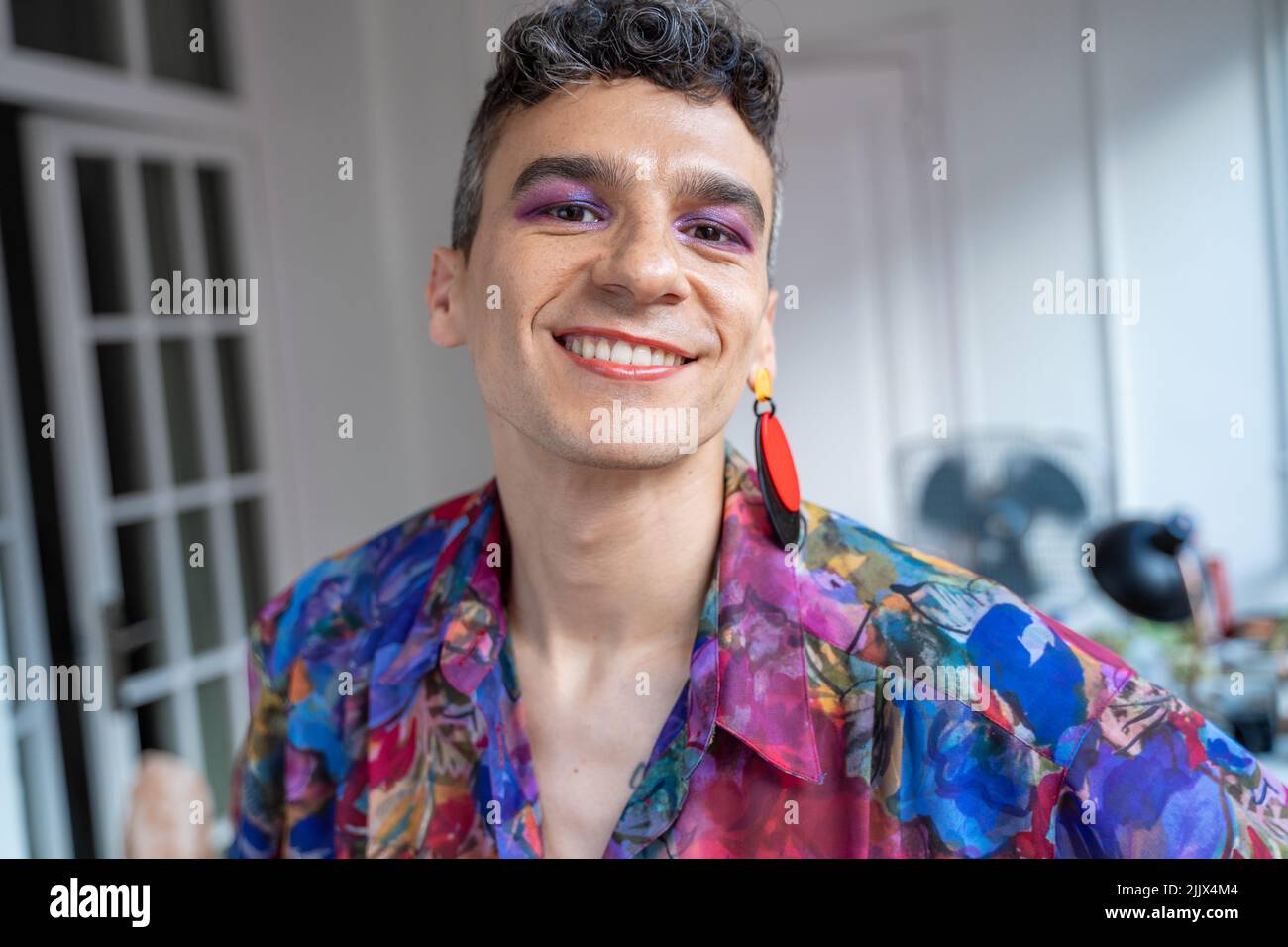 Portrait of confident transgender man in casual sitting on sideboard at ...