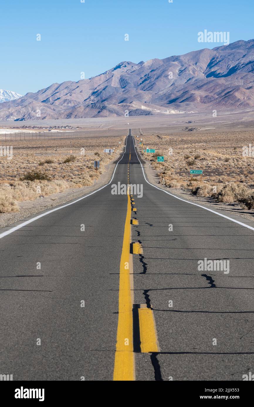 Road leaning rocky mountains amidst barren land at death valley Stock ...