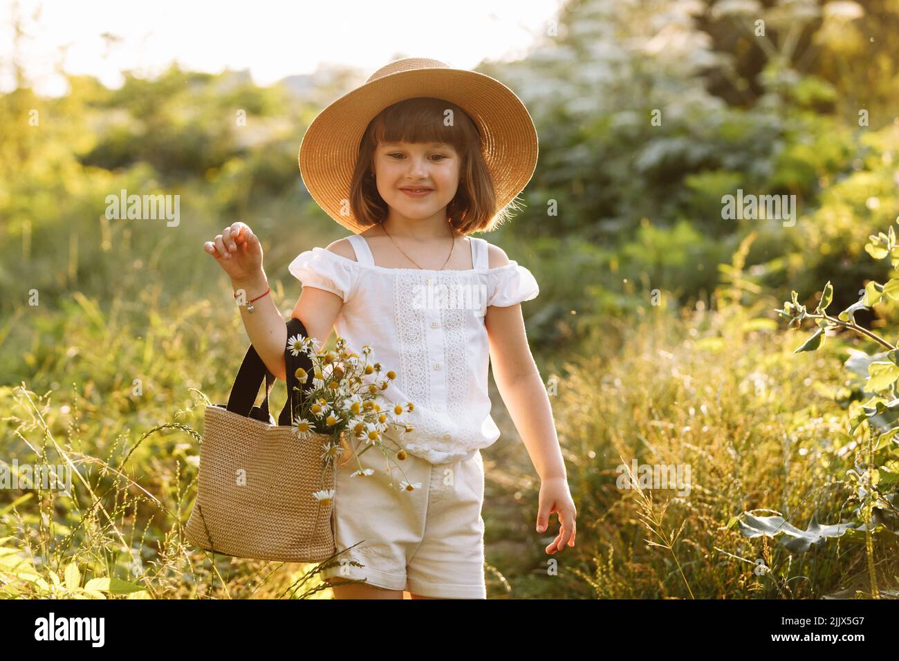 Portrait of smiling little girl walks in the rays of a sunset in a ...