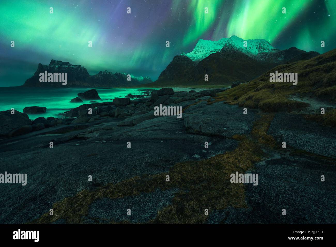 Scenery of rocky cliffs with snowy peaks on shore of North Sea under ...