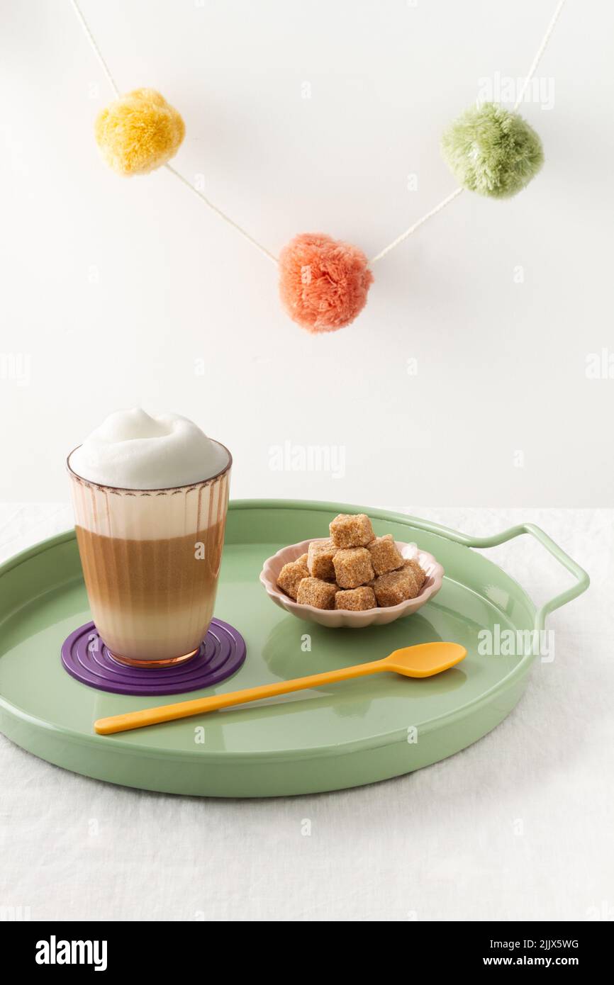 Multilayer coffee or cappuccino in a glass cup and brown sugar cubes in ...