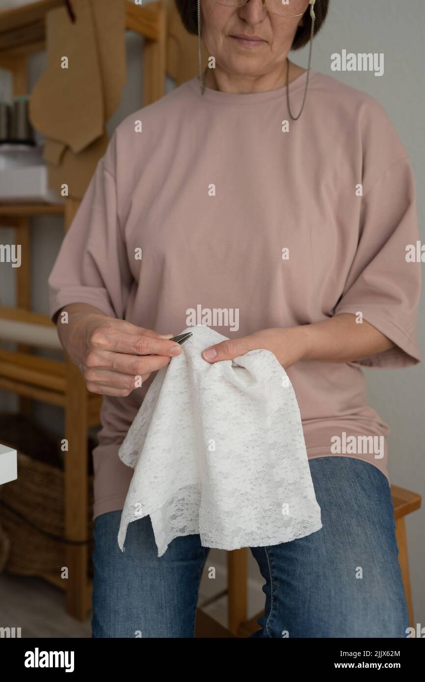 Professional female seamstress in casual wear using thread snips while ...