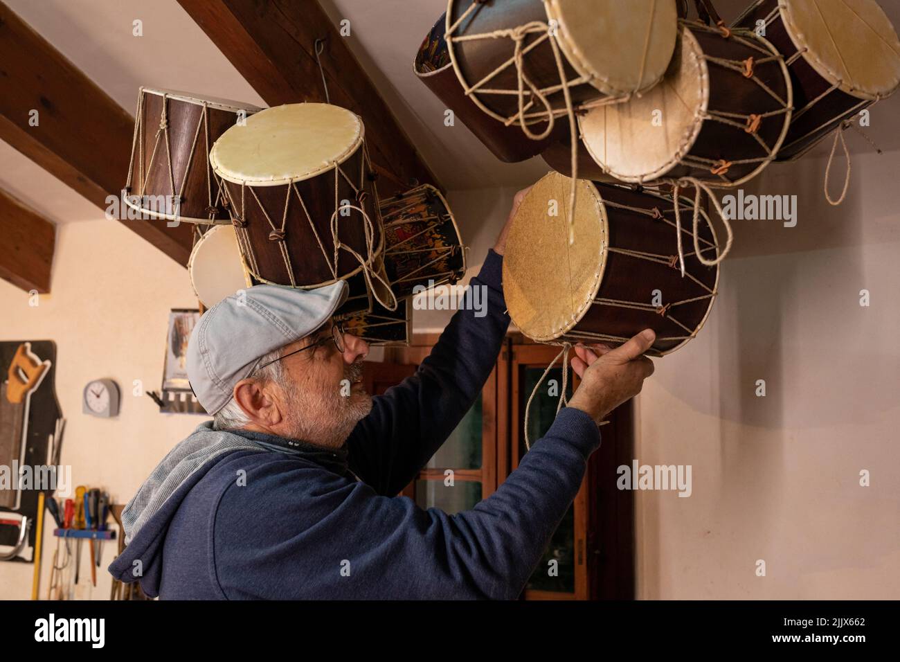 Side view of focused male master in cap hanging traditional Tapan drums ...