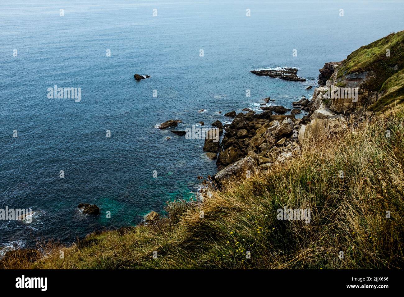 From above of green grassy slope located on rocky shore near rippling ...