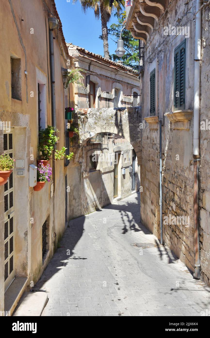 A vertical shot of narrow street between the old houses of Modica, a ...