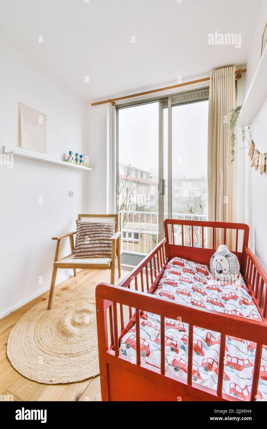 Interior of a room with a wooden crib next to a bright window and white ...