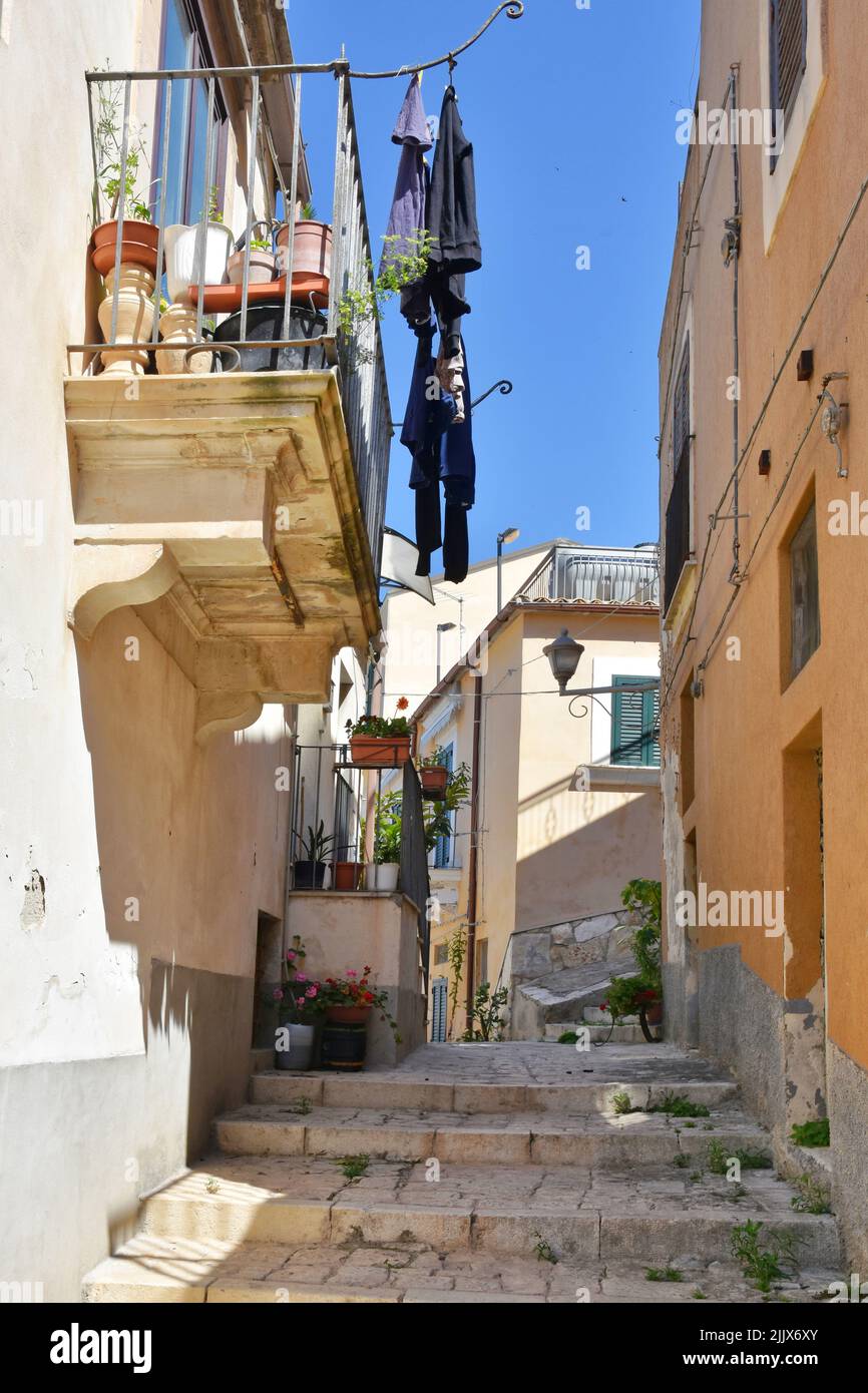 A vertical shot of narrow street between the old houses of Modica, a ...