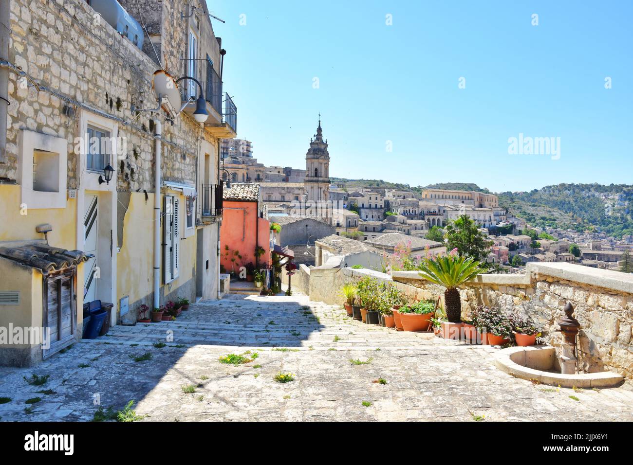 A vertical shot of narrow street between the old houses of Modica, a ...